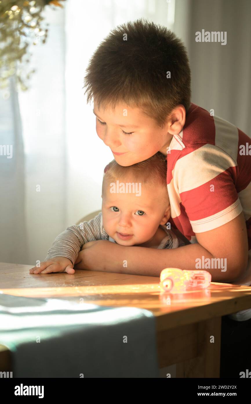 Older brother kissing and hugging his baby boy. Two siblings. Beautiful ...