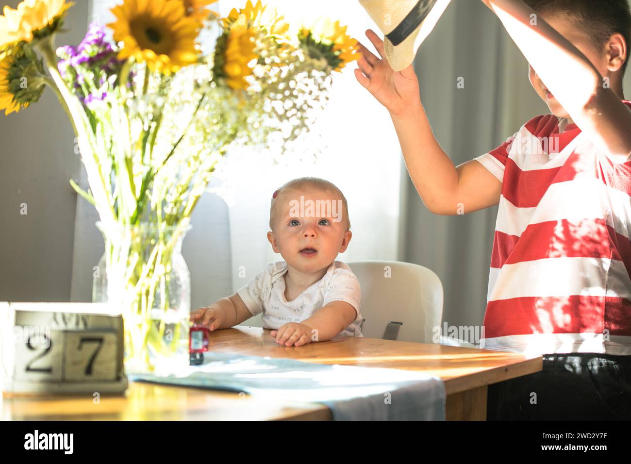 Brother boys on the windowsill by window, older brother hugs younger ...