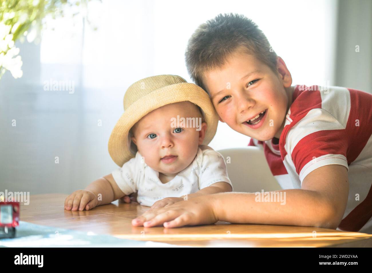 Brother boy take care of his baby brother, hugs him Stock Photo - Alamy