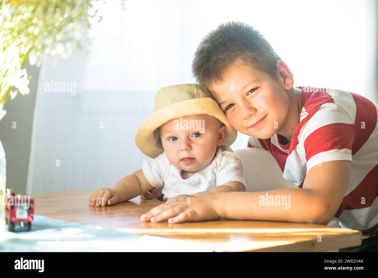 Brother boy take care of his baby brother, hugs him Stock Photo - Alamy