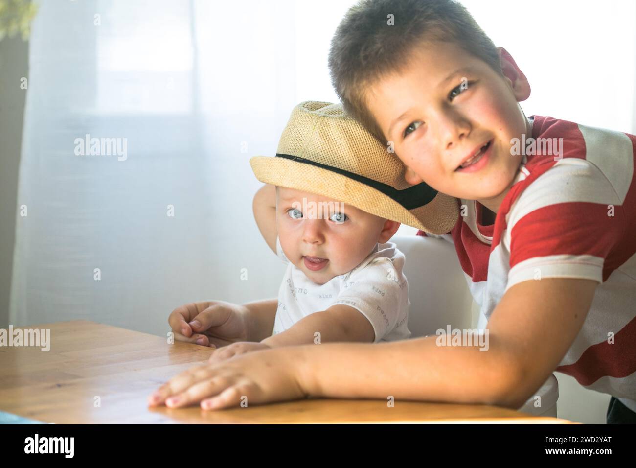 Brother boy take care of his baby brother, hugs him Stock Photo - Alamy