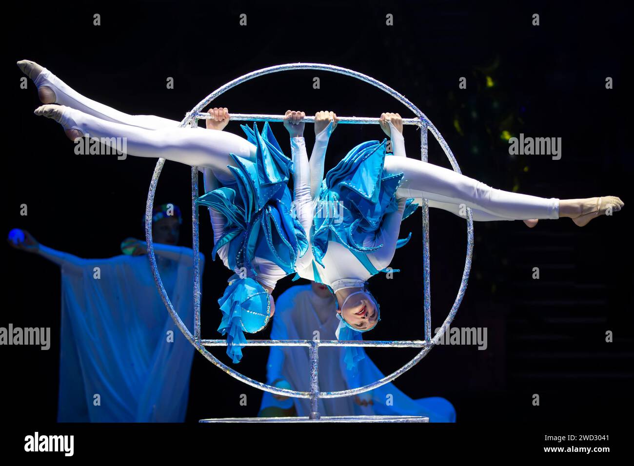 Two acrobat girls show a circus number on a dark background. Acrobatic ...