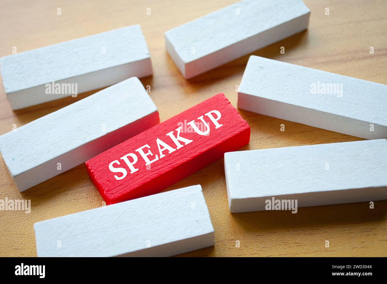 Speak up text on red wooden block surrounded by white wooden blocks. Courage culture concept ...