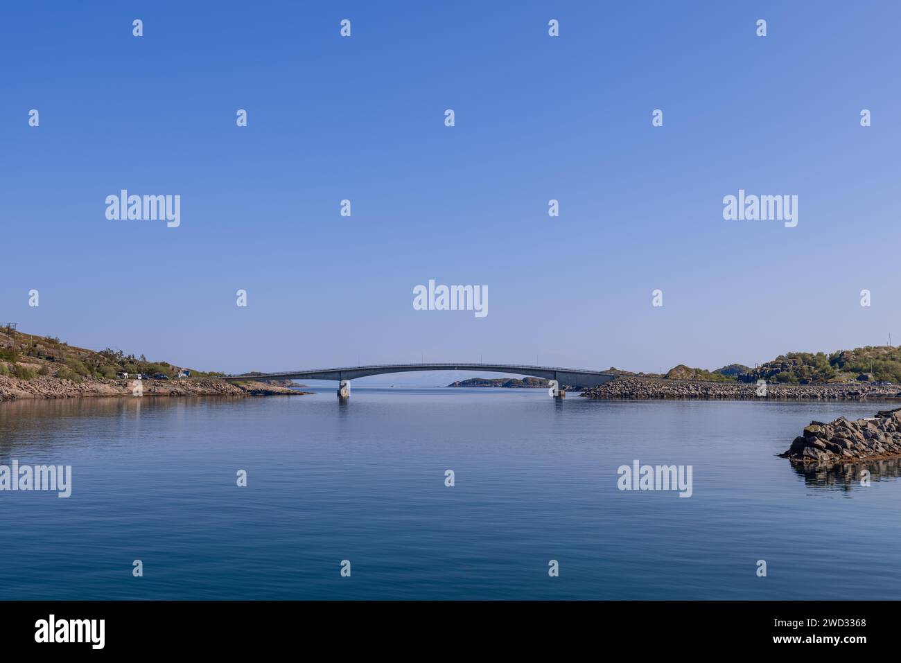 A slender bridge arches gracefully over the still waters of Lofoten ...