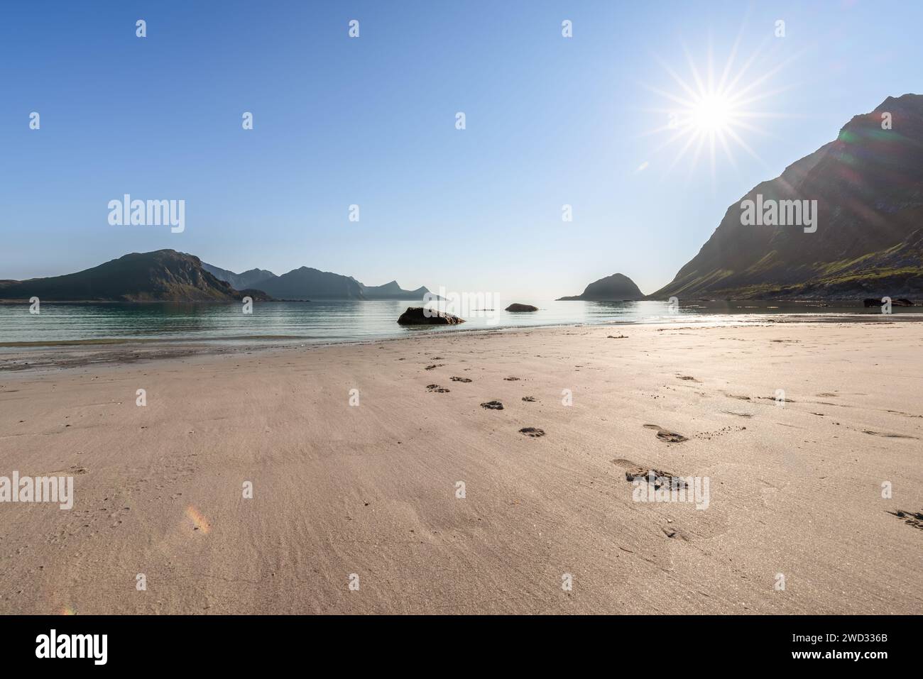 Sunlit path of footprints leading to the water's edge at Haukland Beach ...