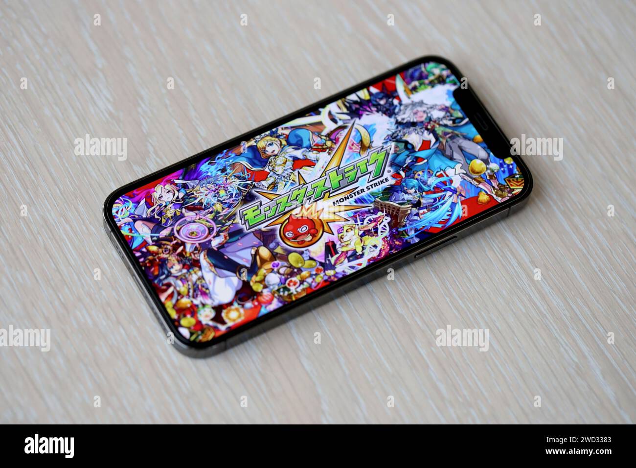 Monster Strike mobile iOS game on iPhone 15 smartphone screen on wooden ...