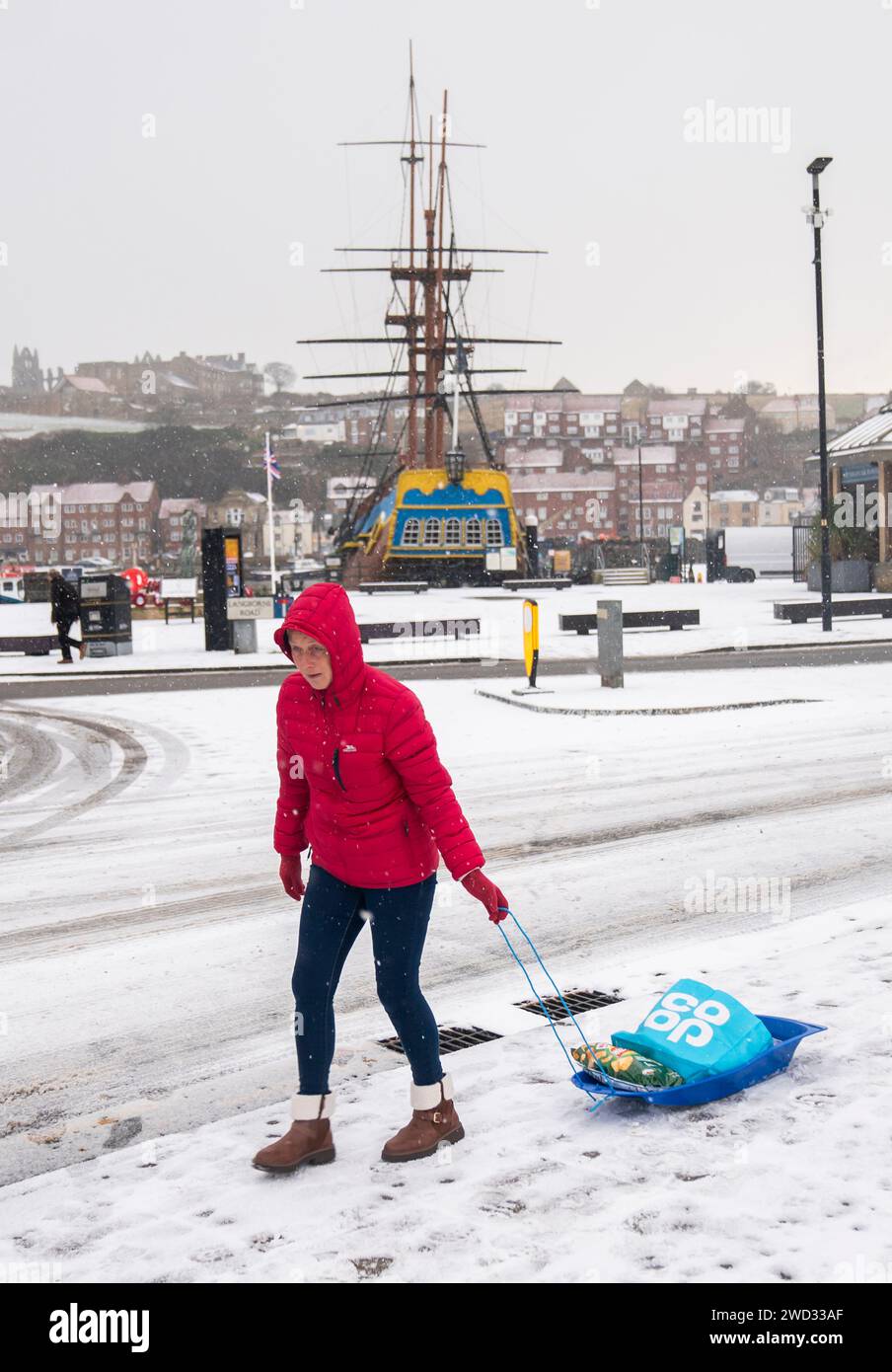 A person pulls a sled through snow in Whitby. Hundreds of schools are ...