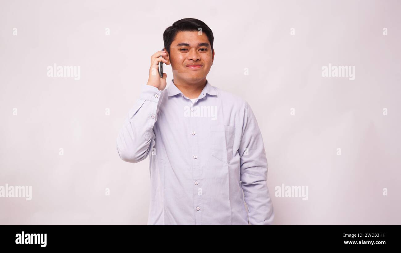 Asian man smiling at camera while answering a mobile phone call on ...