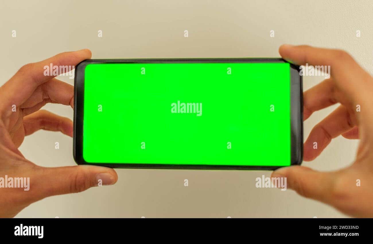 Female hands are holding smartphone with green screen mock up on ...