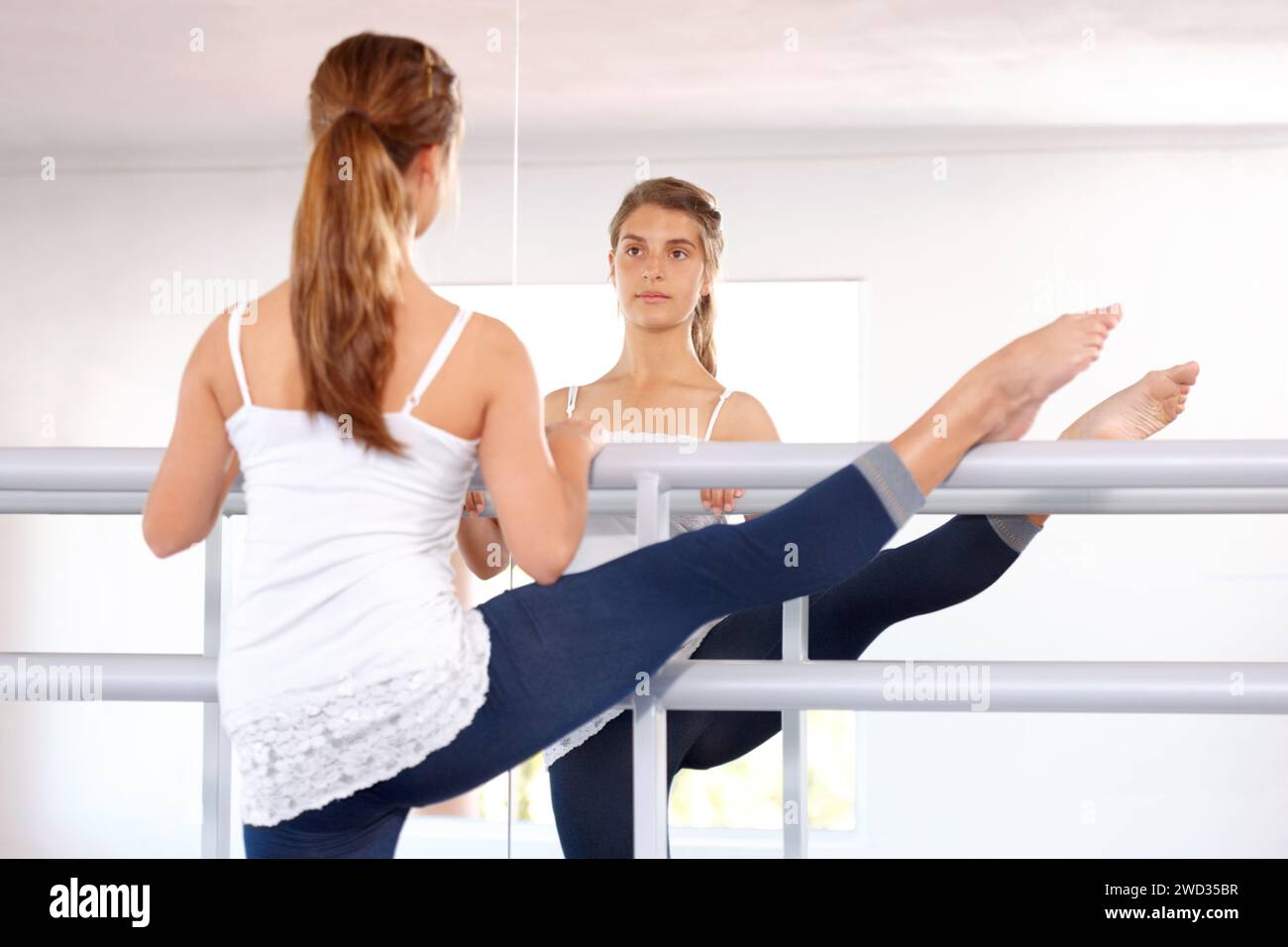 Stretching legs, ballet and reflection of girl in studio, barre and ...