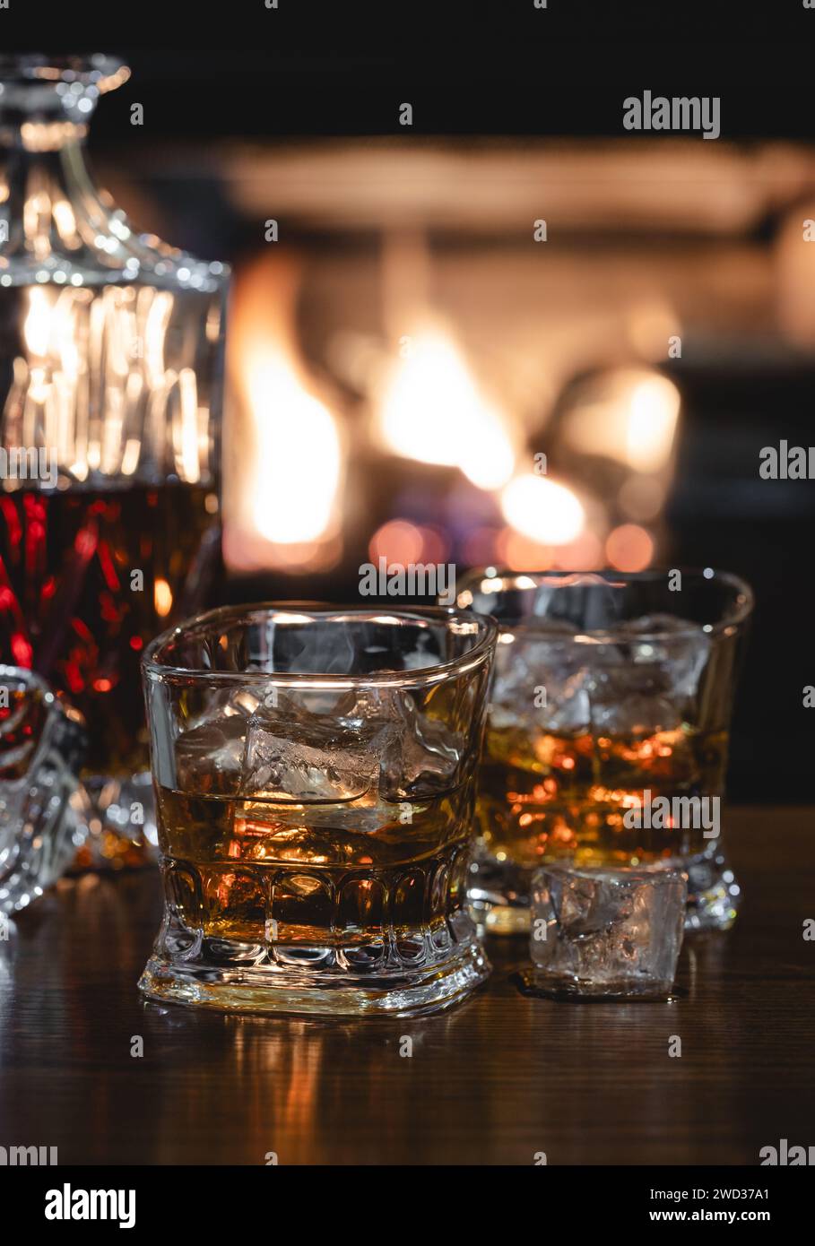 Two glasses of wiskey with ice and decanter on wooden table with ...