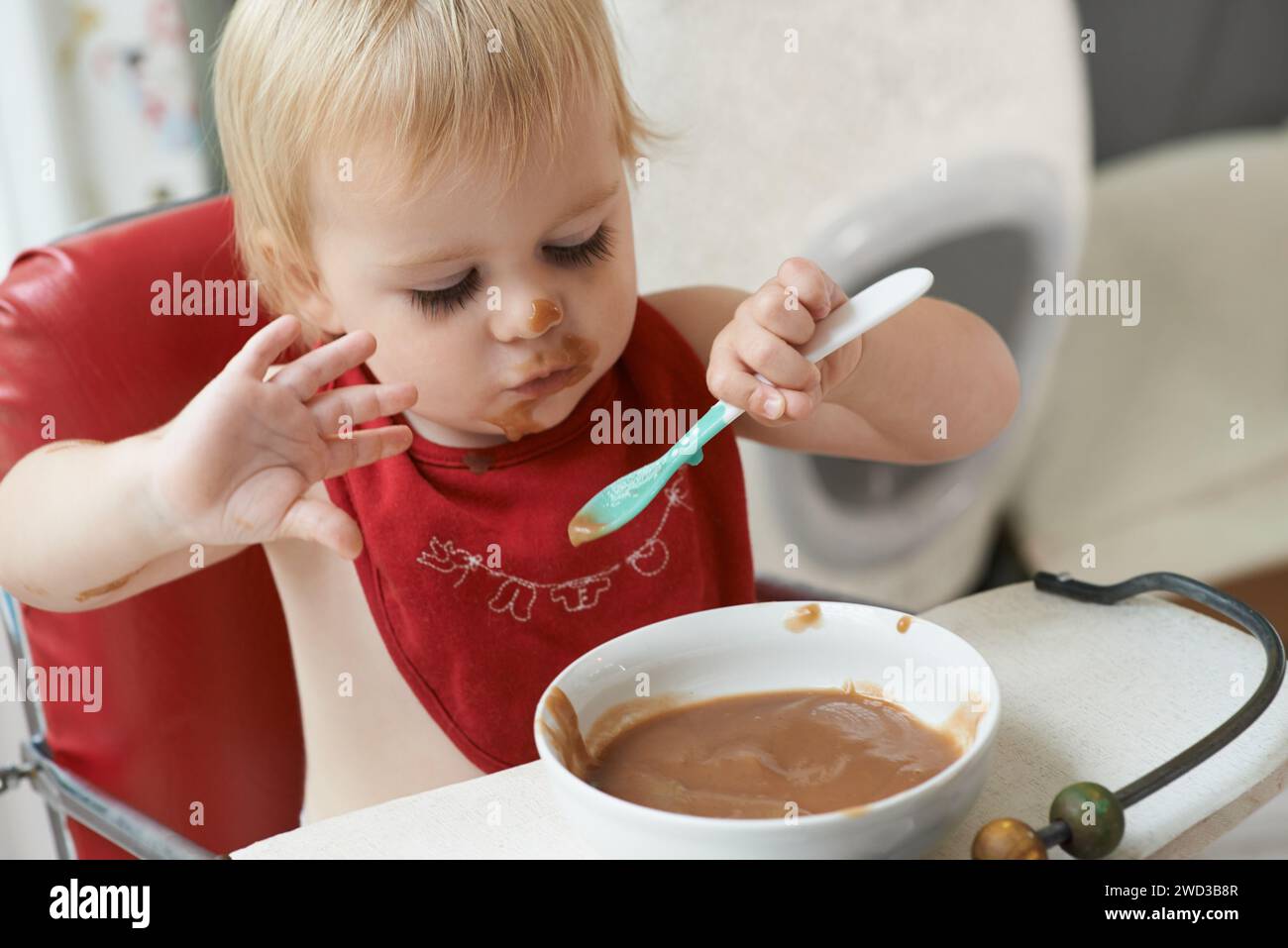 High chair, eating and baby with spoon in a house for nutrition, diet ...