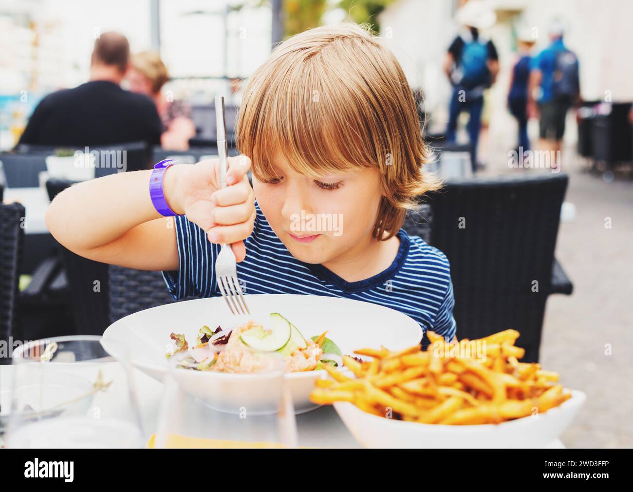 Little boy having lunch in the restaurant, child eating fresh salmon ...