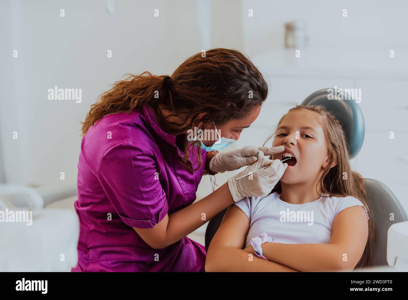 A cheerful girl undergoes a dental examination in a modern pediatric ...