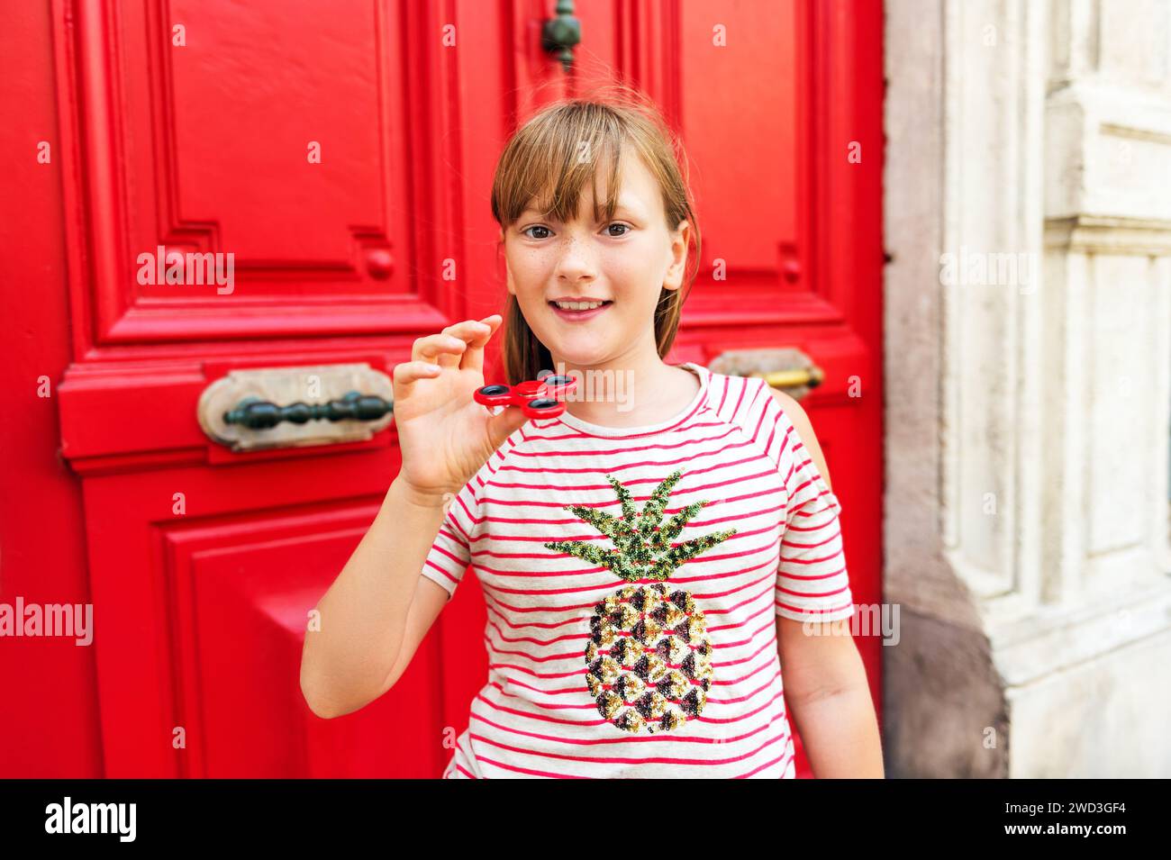 Cute school girl playing with red fidget spinner. Popular stress ...