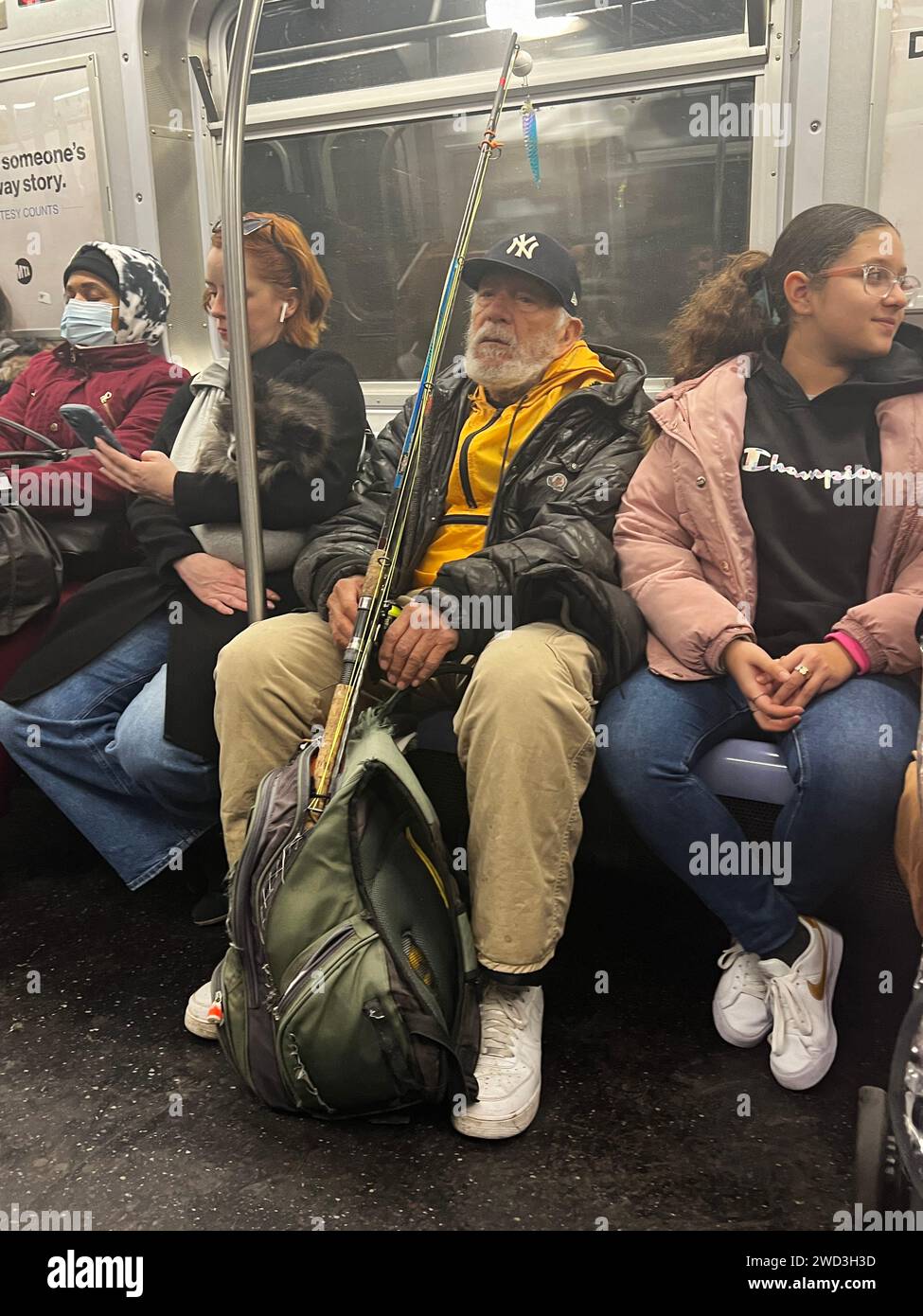 Man with a fishing rod rides a crowded subway train in Brooklyn during ...