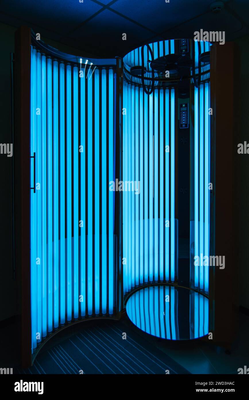 vertical Solarium with glowing blue light ultraviolet lamps for tanning ...