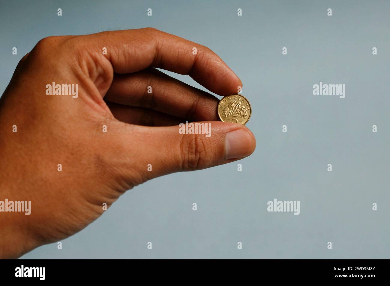 Close up hand holding five cent dollar coin singapore Stock Photo - Alamy