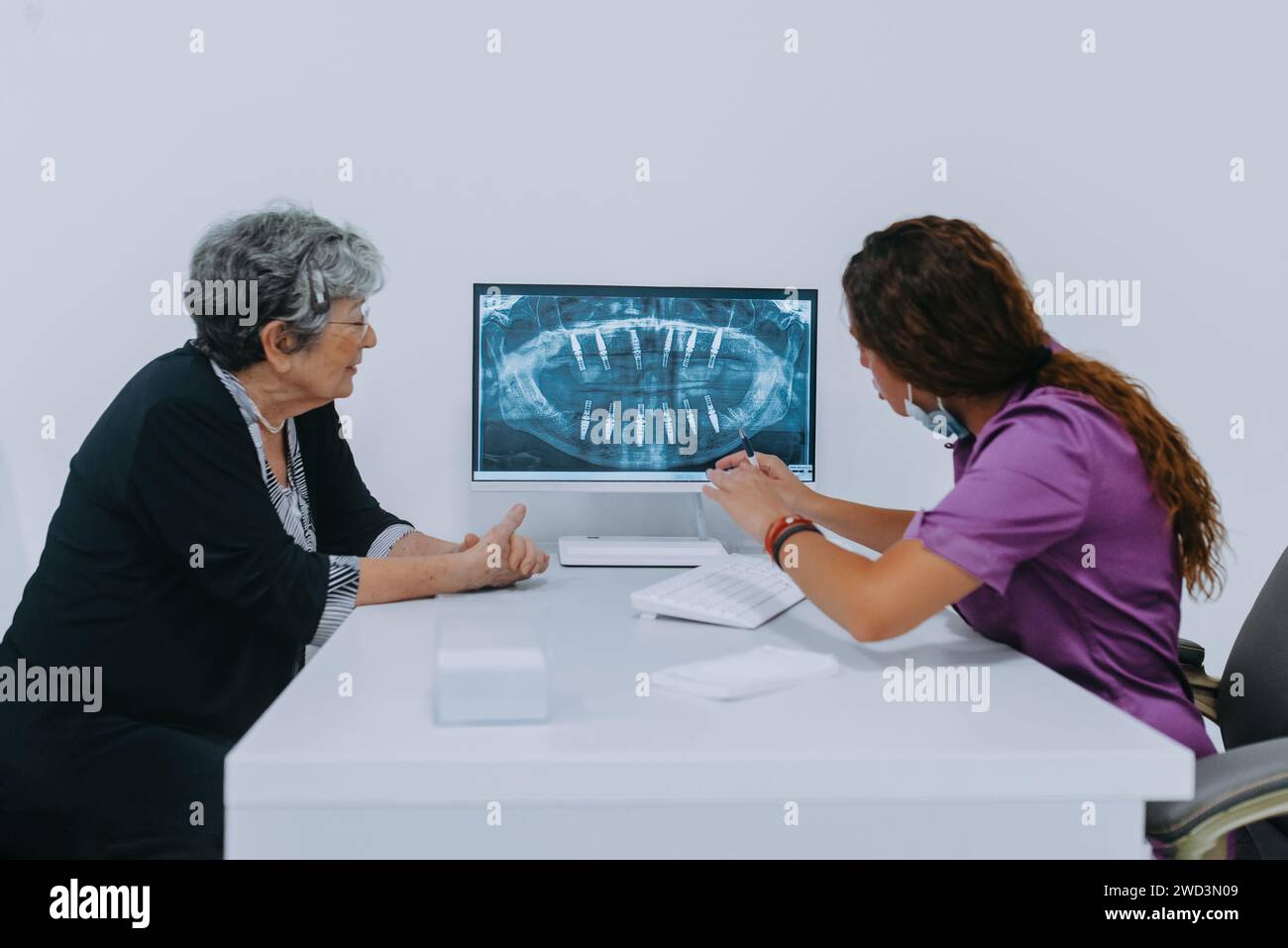 Elderly lady consults with her dentist in a dental office, discussing ...