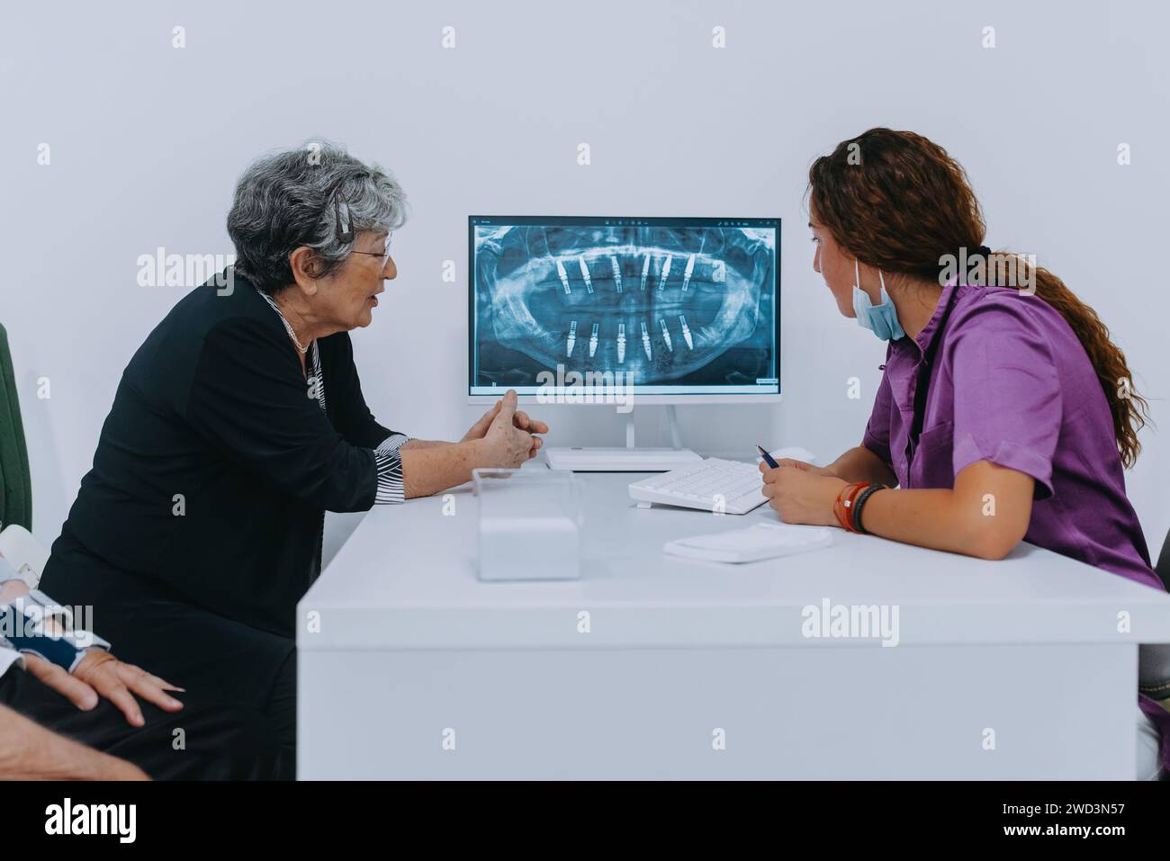Elderly lady consults with her dentist in a dental office, discussing ...