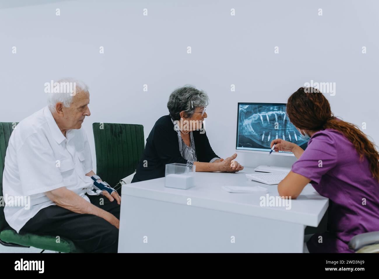 An elderly couple engages in a thoughtful discussion with their dentist ...