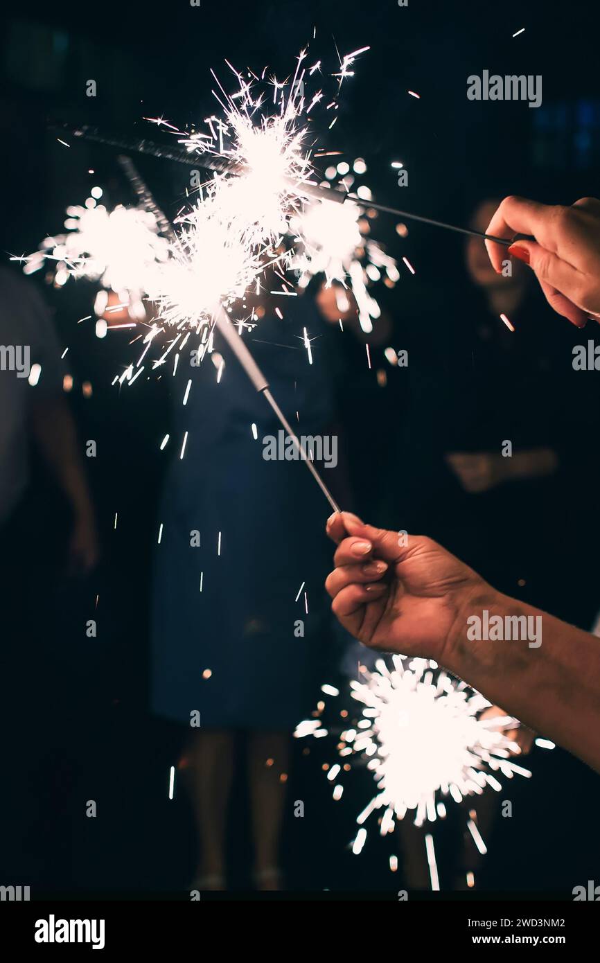 Bengal lights in the hands of people with sparks of fire on holiday on ...