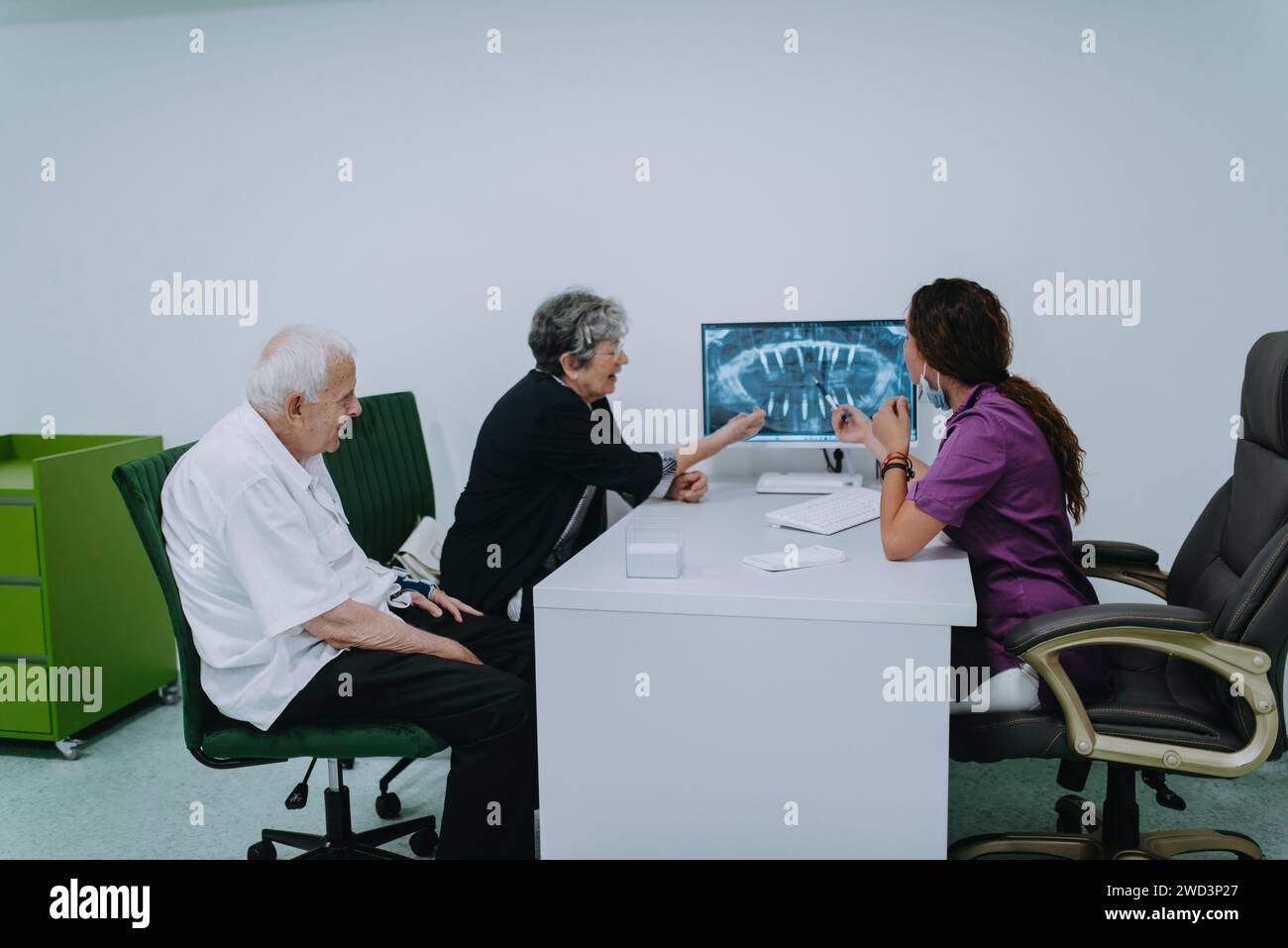 An elderly couple engages in a thoughtful discussion with their dentist ...