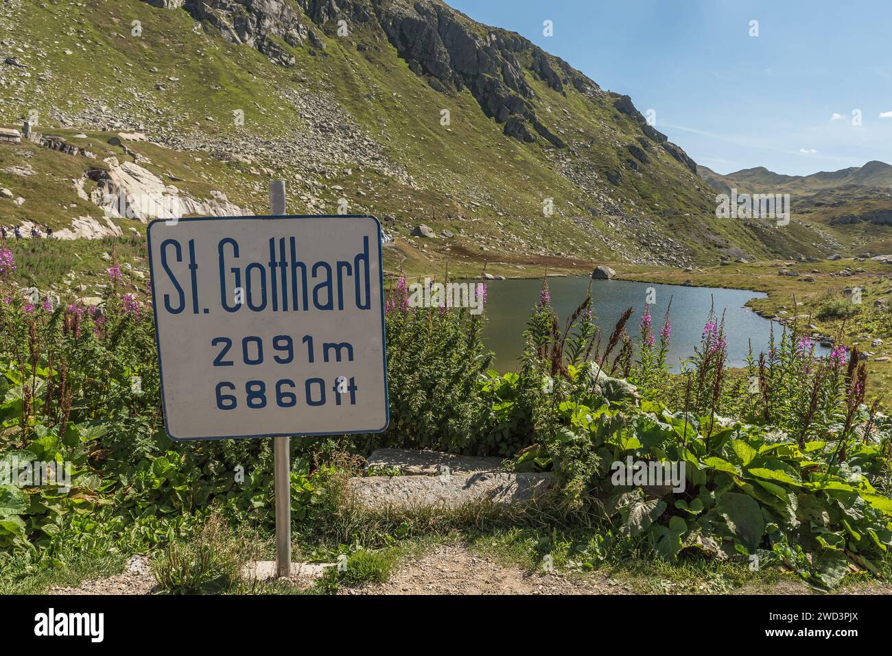 Mountain lake at the top of the Gotthard Pass, old place-name sign with ...