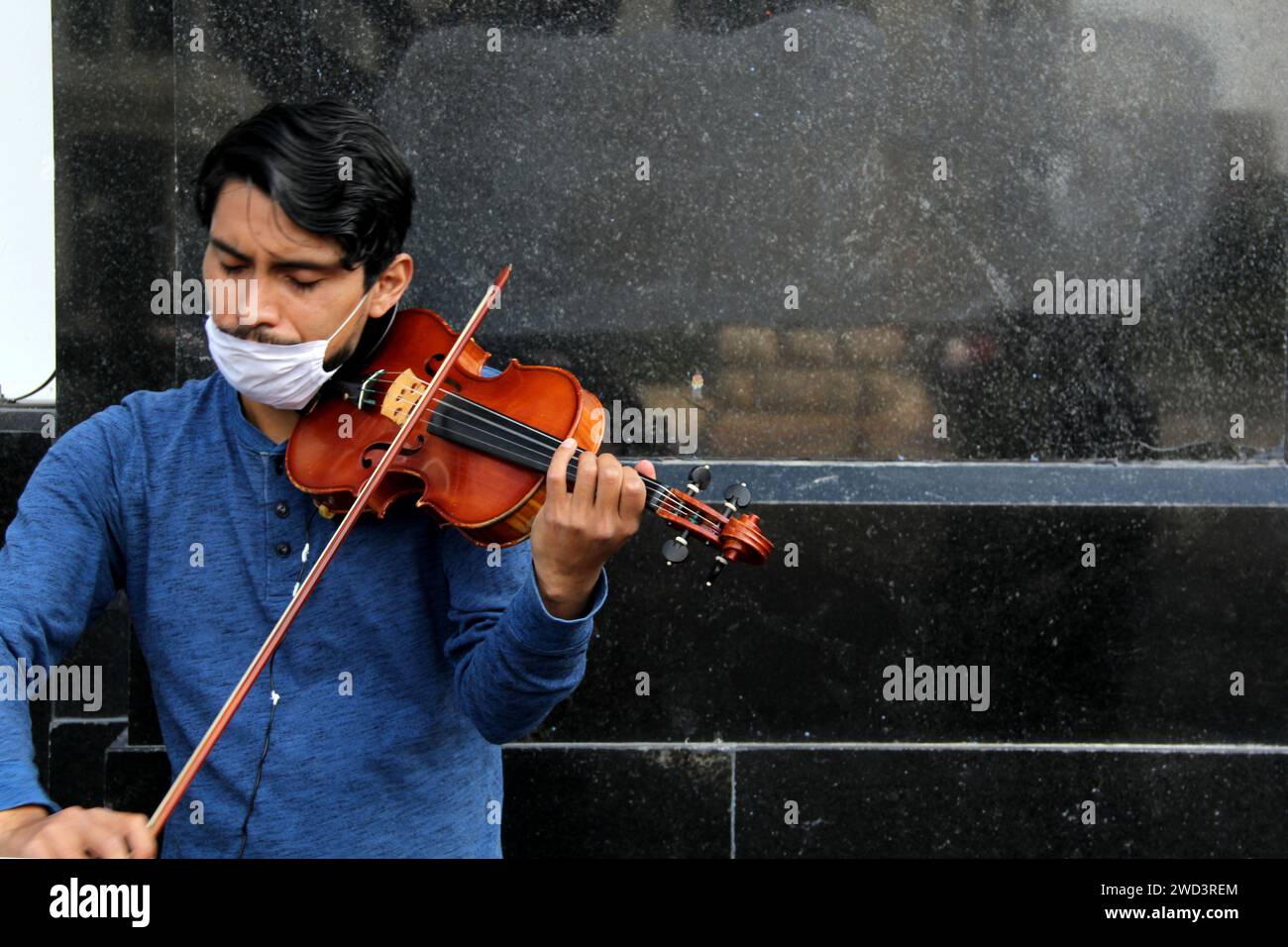 Latin man with protection mask playing musical instrument violin in the ...