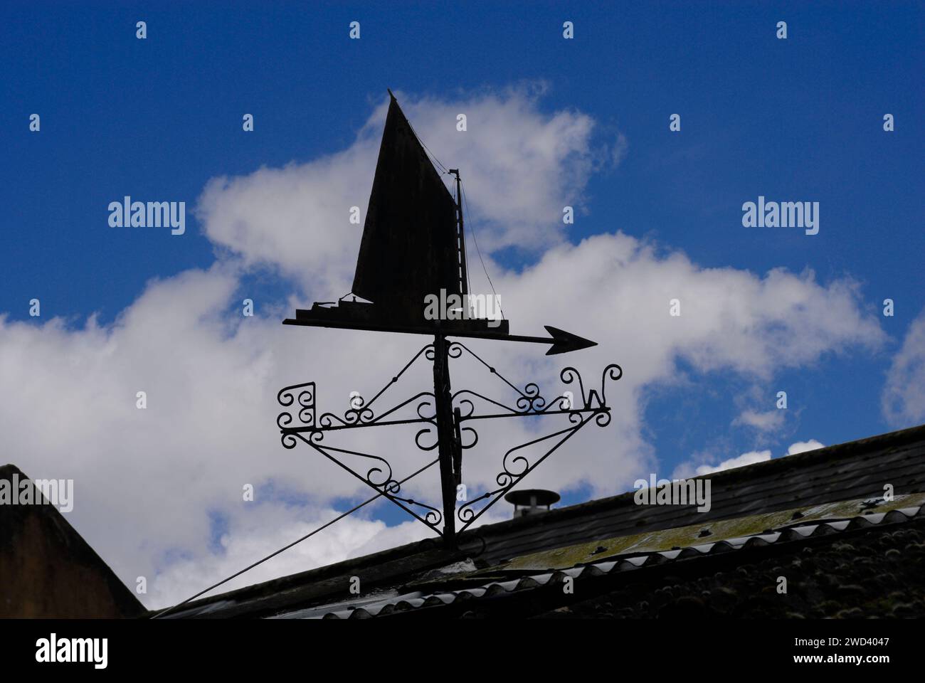 Weather vane in form of sailing boat with mainsail hoisted seen in ...