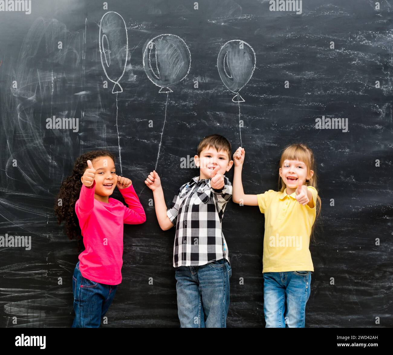 three smiling children with thumbs up keeping imaginaru drawn balloons ...