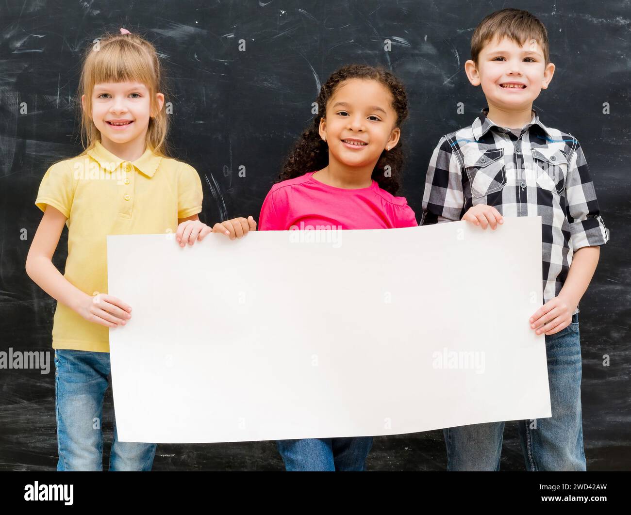 three cute children holding an empty paper sheet for ad with chalky ...