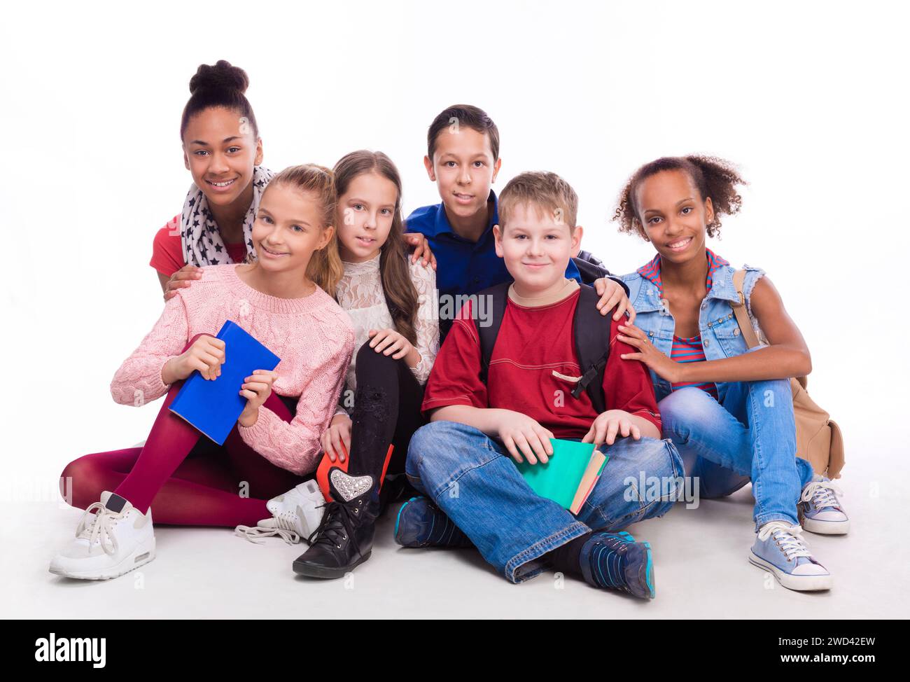 group of schoolmates sitting on the floor isolated on white background ...