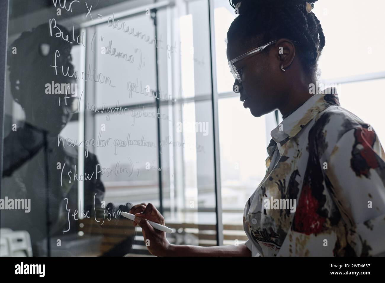 Young african american office employee writing code with white marker ...