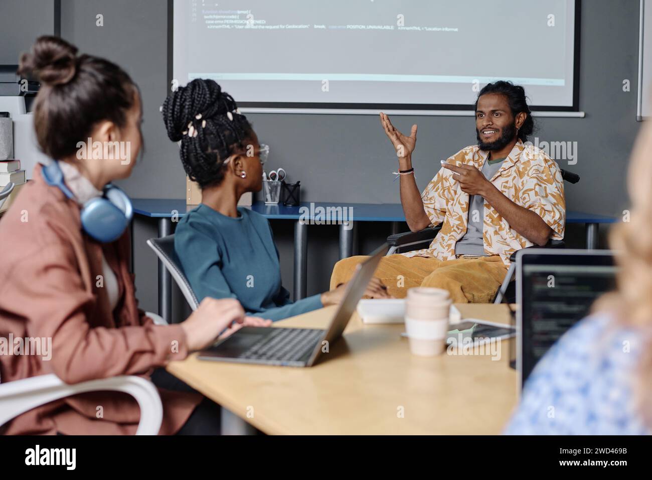 Joyful indian programmer in wheelchair demonstrating code on digital ...