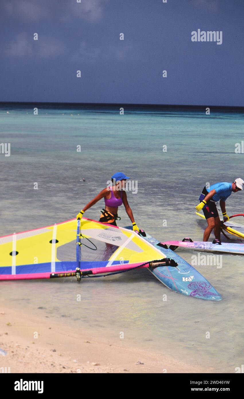 A female windsurfing student learning to rig her board in Aruba ca ...