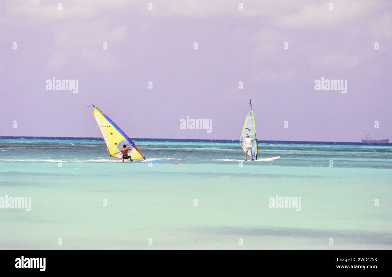 Long shot of two windsurfers (boardsailors) crossing in the blue waters ...