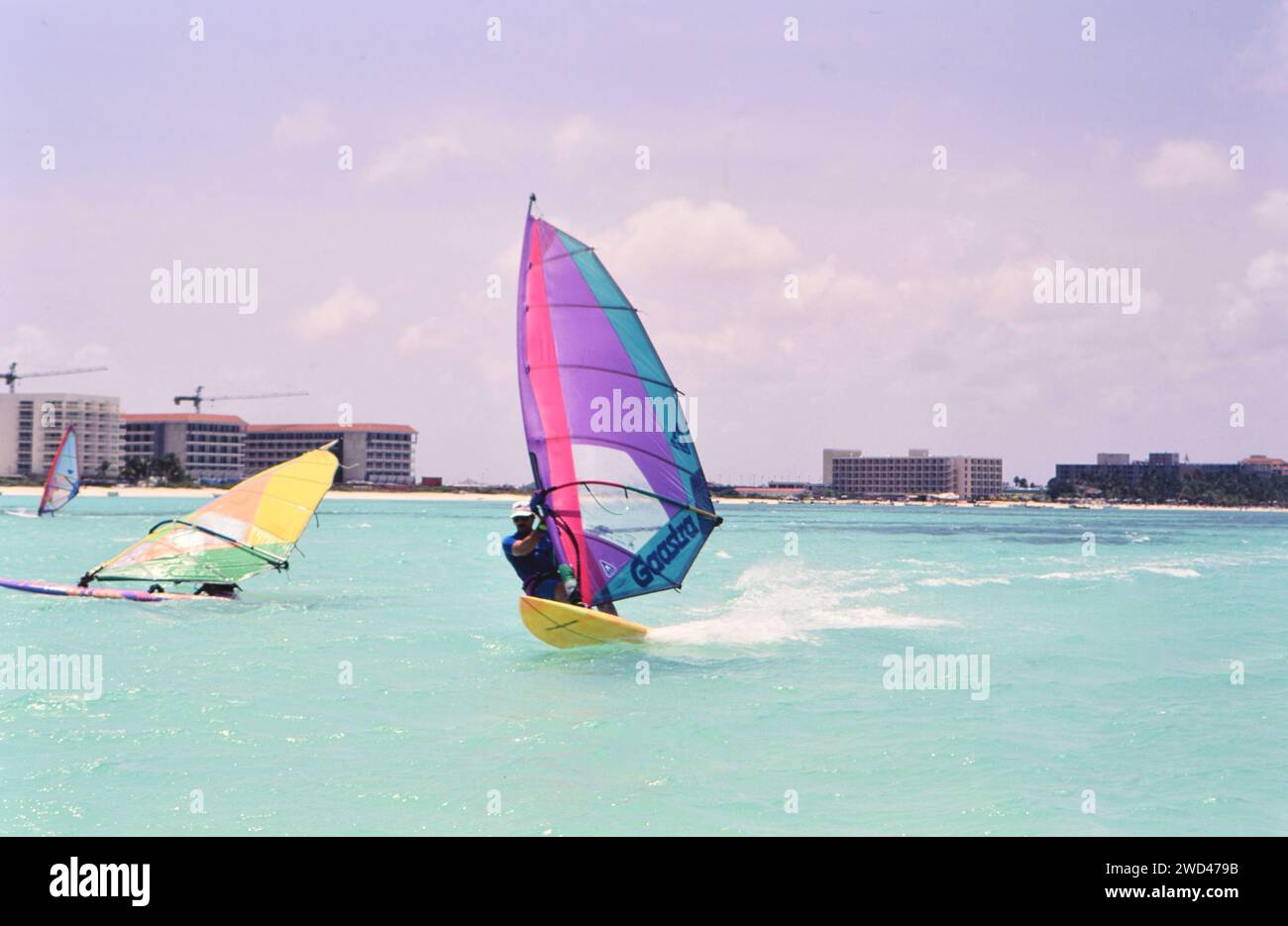 Two young men windsurfing (boardsailing) in the blue waters off of ...