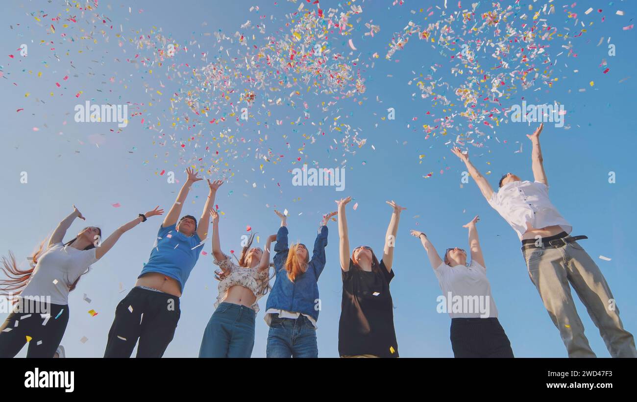 Friends toss colorful paper confetti from their hands Stock Photo - Alamy