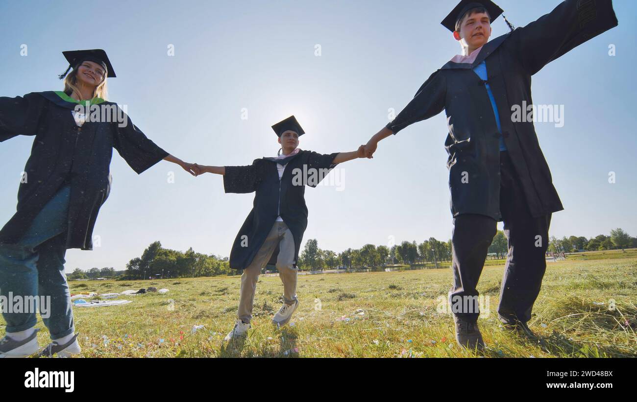 College graduates holding hands run in a round dance Stock Photo - Alamy
