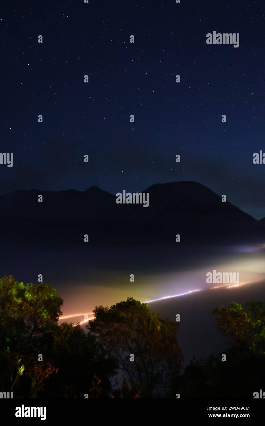 Nighttime view of Mount Bromo enveloped in fog, with car lights ...