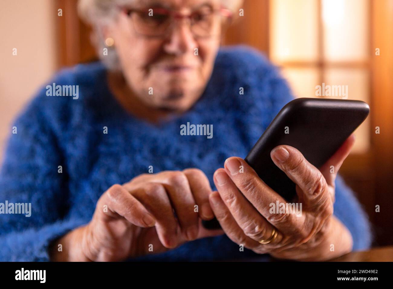 Elderly woman using a mobile phone over wood table at living room of ...