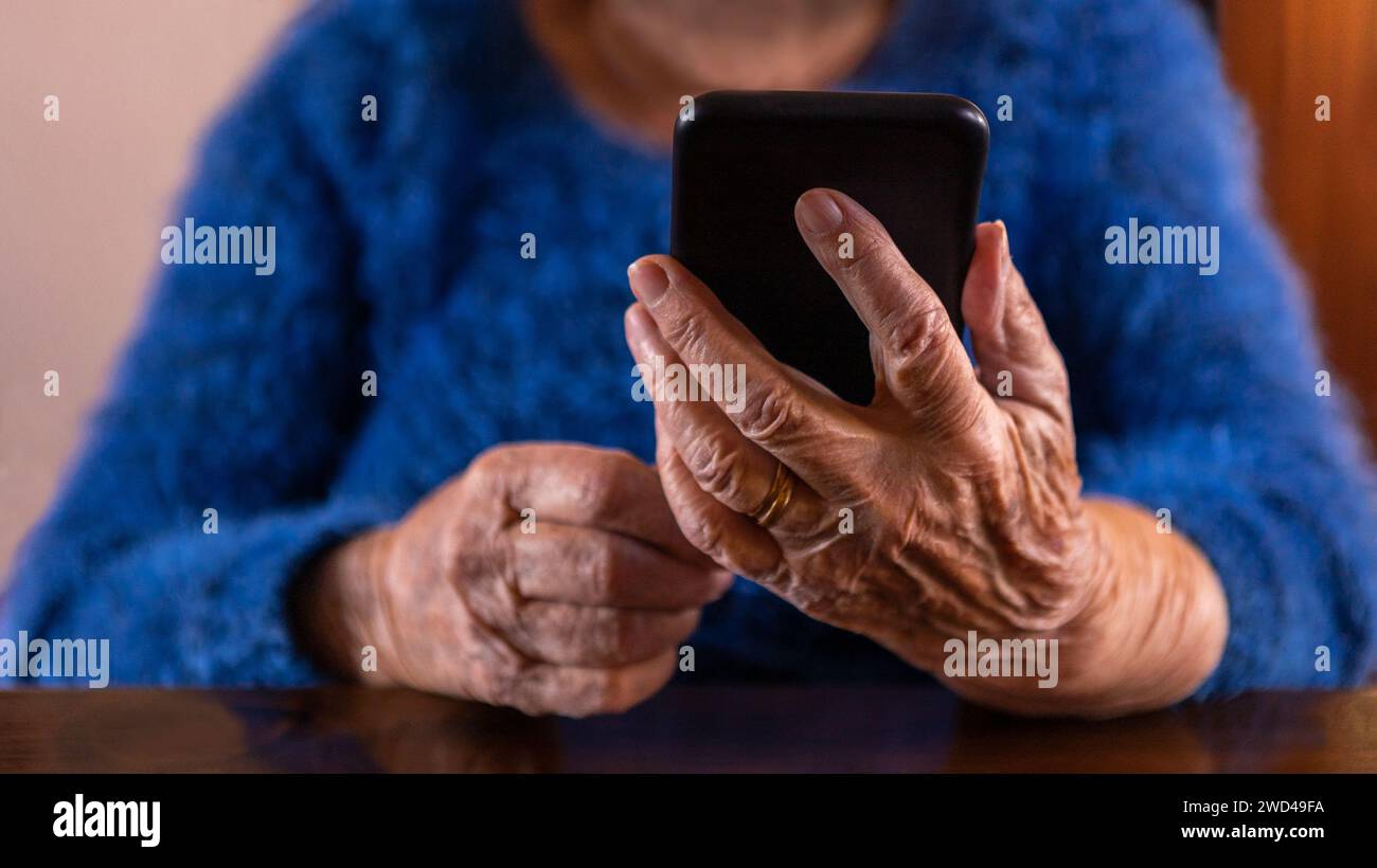 Elderly woman using a mobile phone over wood table at living room of ...