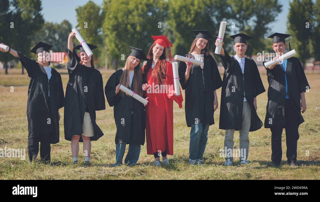 Young graduates pose with diplomas in hand on the street Stock Photo ...