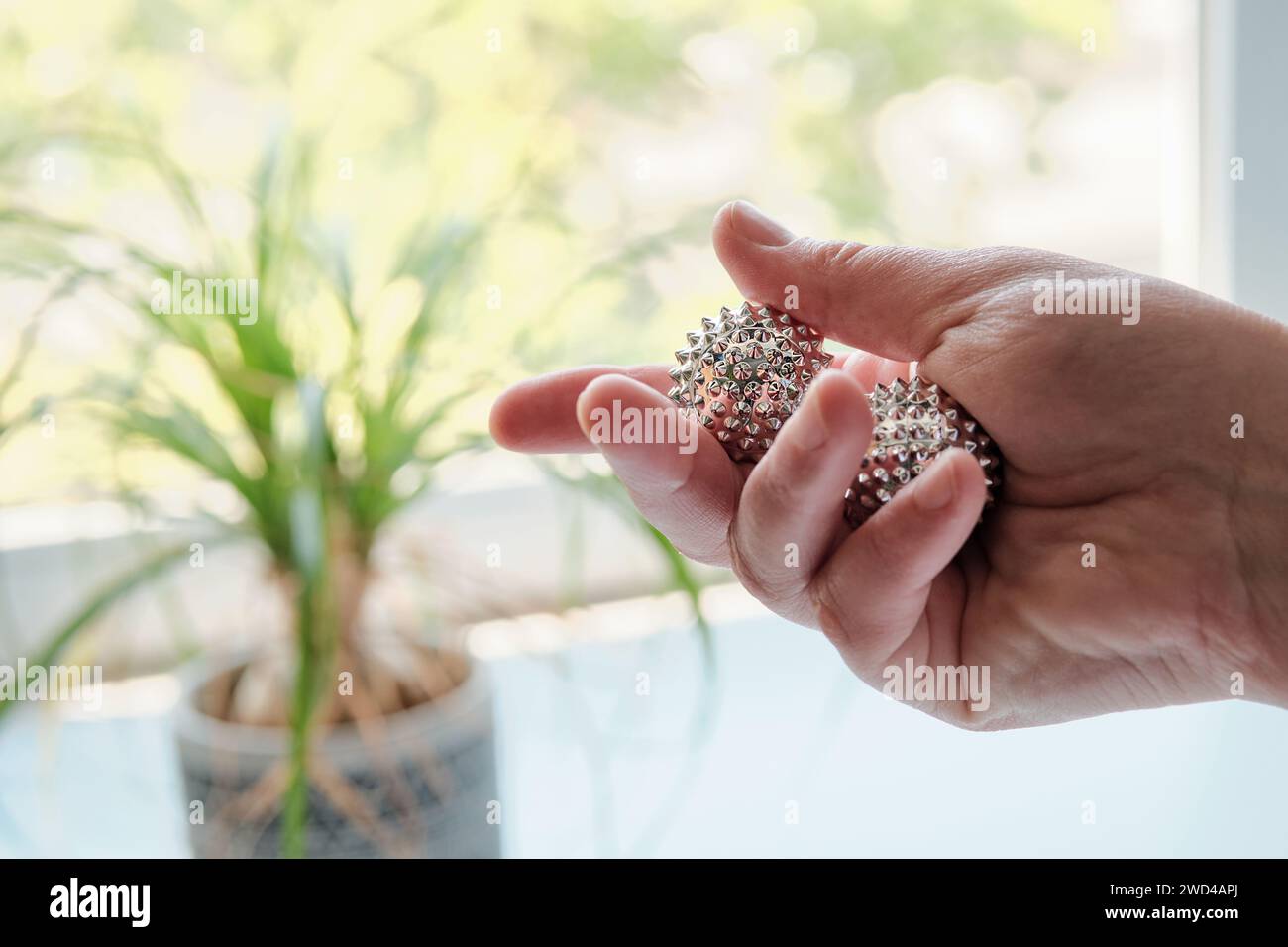 Silver metal magnetic balls in female hand. Spiky tool for hand massage ...