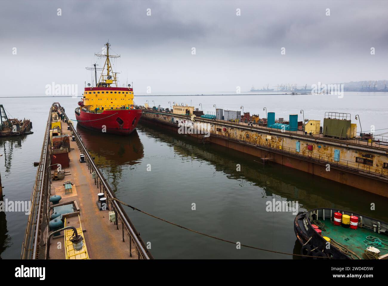 Icebreaker enters floating dock at shipyard for repairs, overcast sky ...