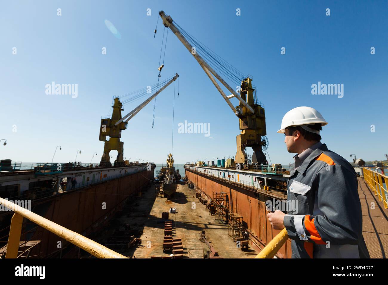 Professional overseeing extensive shipbuilding process, massive cranes ...