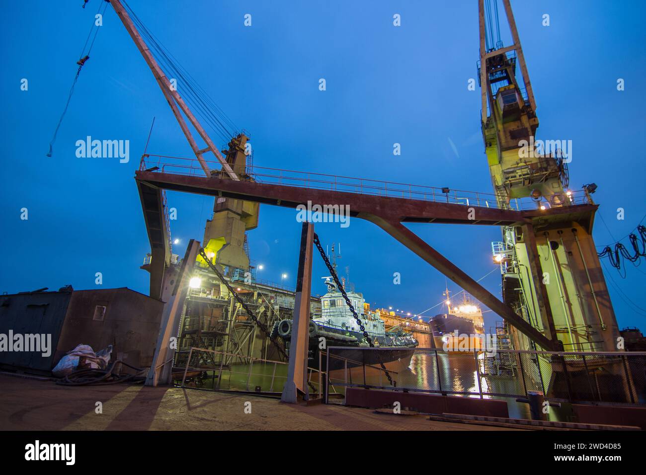 Industrial ship repair yard at night, floating dock lit up, vessel ...