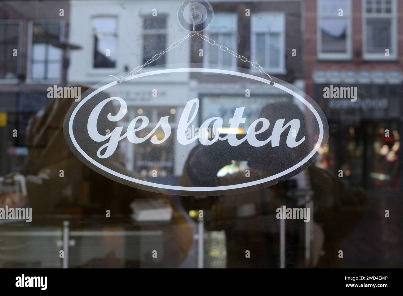 Closed sign hanging on a chain in the door of a dutch shop. Gesloten is ...