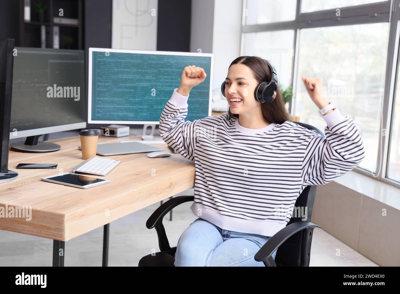 Pretty young female programmer celebrating success in office Stock Photo - Alamy